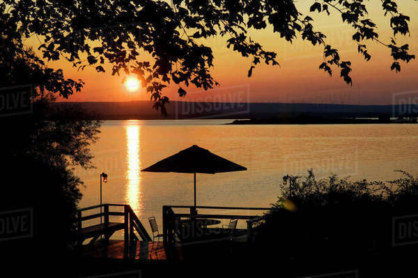 Deck silhouetted against lake at sunset, Grand Isle, Vermont, USA ...