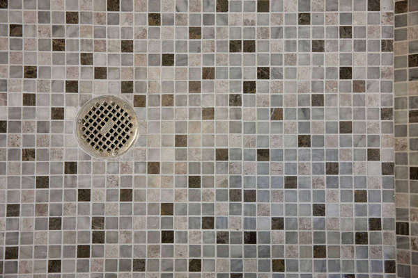 Close-up of drain in mosaic tile floor in the bathroom at home ...