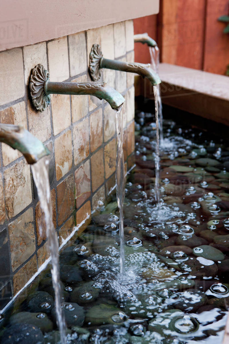 Water flowing from fountains outside house - Stock Photo - Dissolve