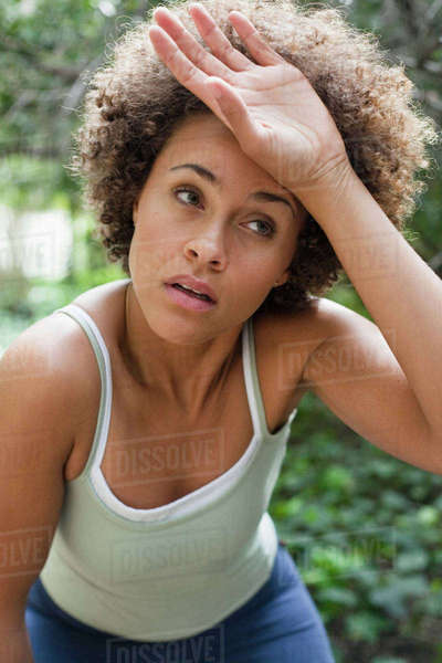 Mixed race woman wiping forehead - Stock Photo - Dissolve