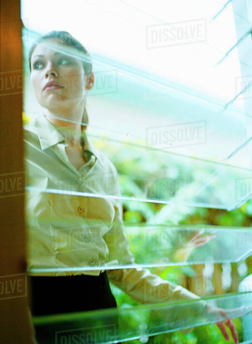 Woman behind window in greenhouse - Stock Photo - Dissolve
