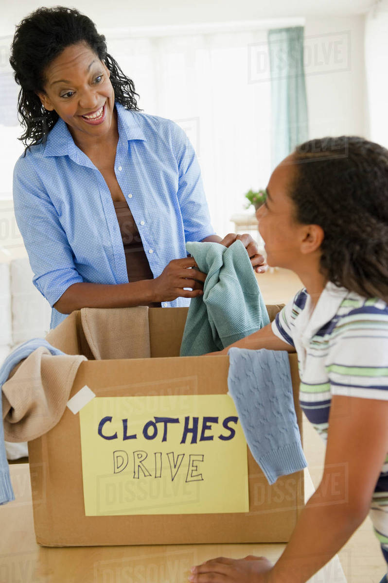 Mother and daughter sorting clothes for clothes drive - Royalty-free ...
