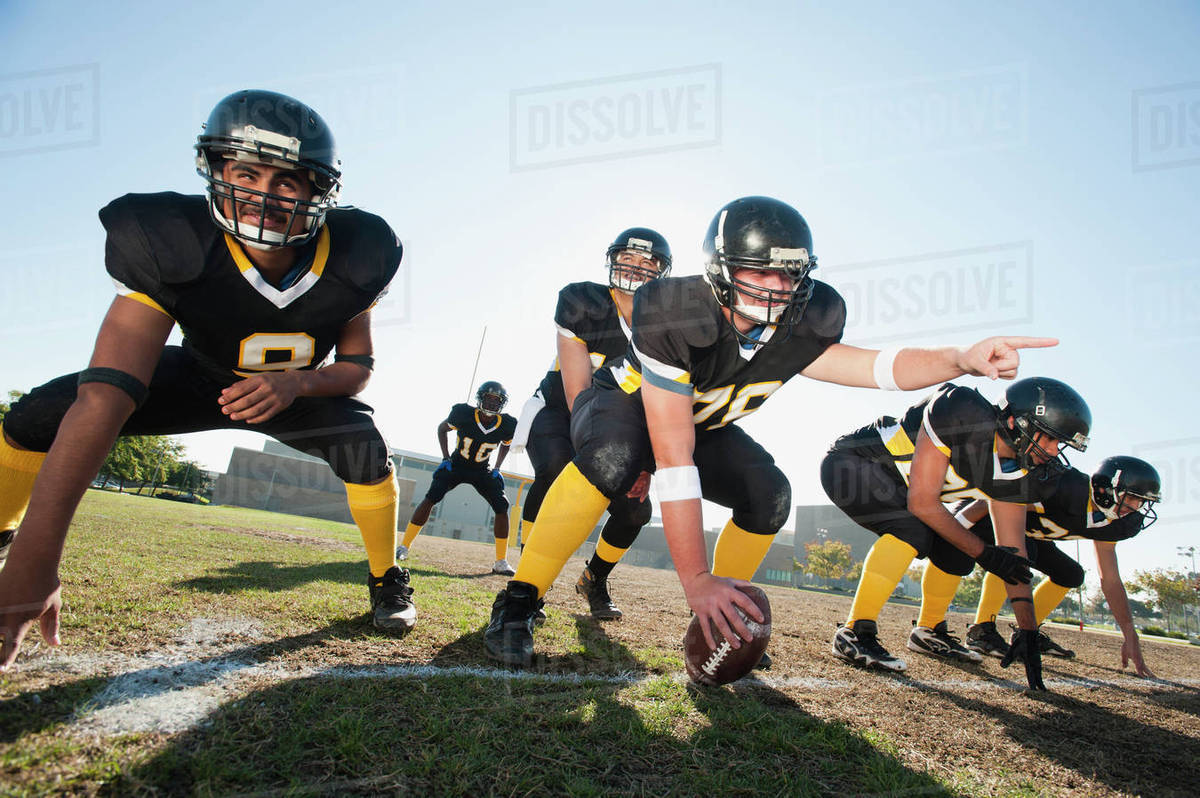 Football players crouching on football field - Stock Photo - Dissolve