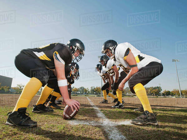 Football players crouching on football field - Stock Photo - Dissolve
