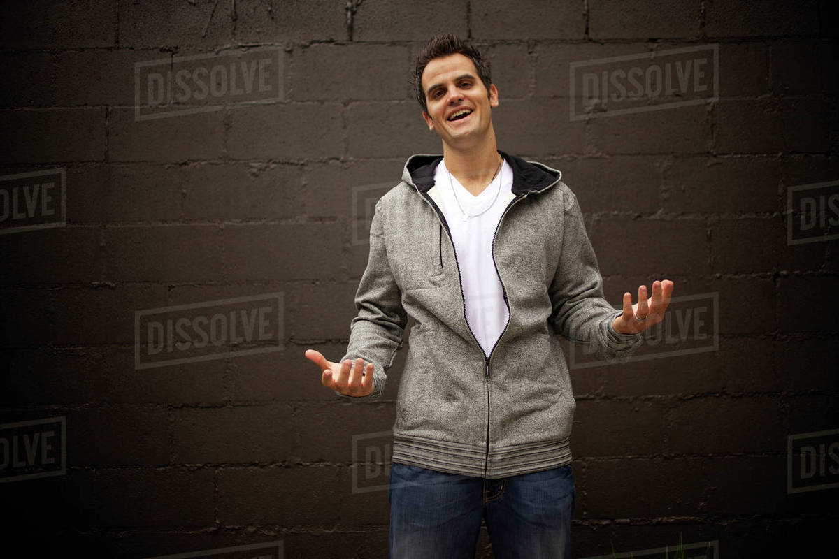 Smiling Caucasian man shrugging - Stock Photo - Dissolve