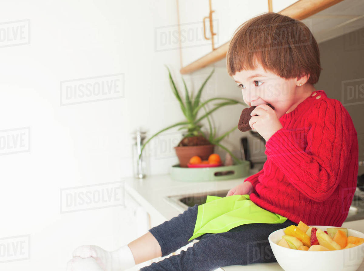 Mixed race boy eating brownie - Royalty-free Stock Photo | Dissolve