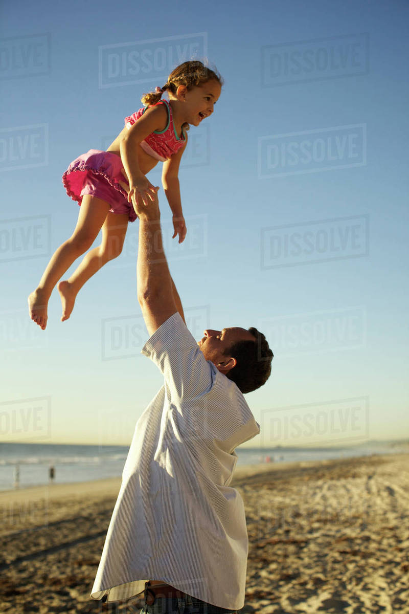 Father lifting daughter in air on beach - Stock Photo - Dissolve