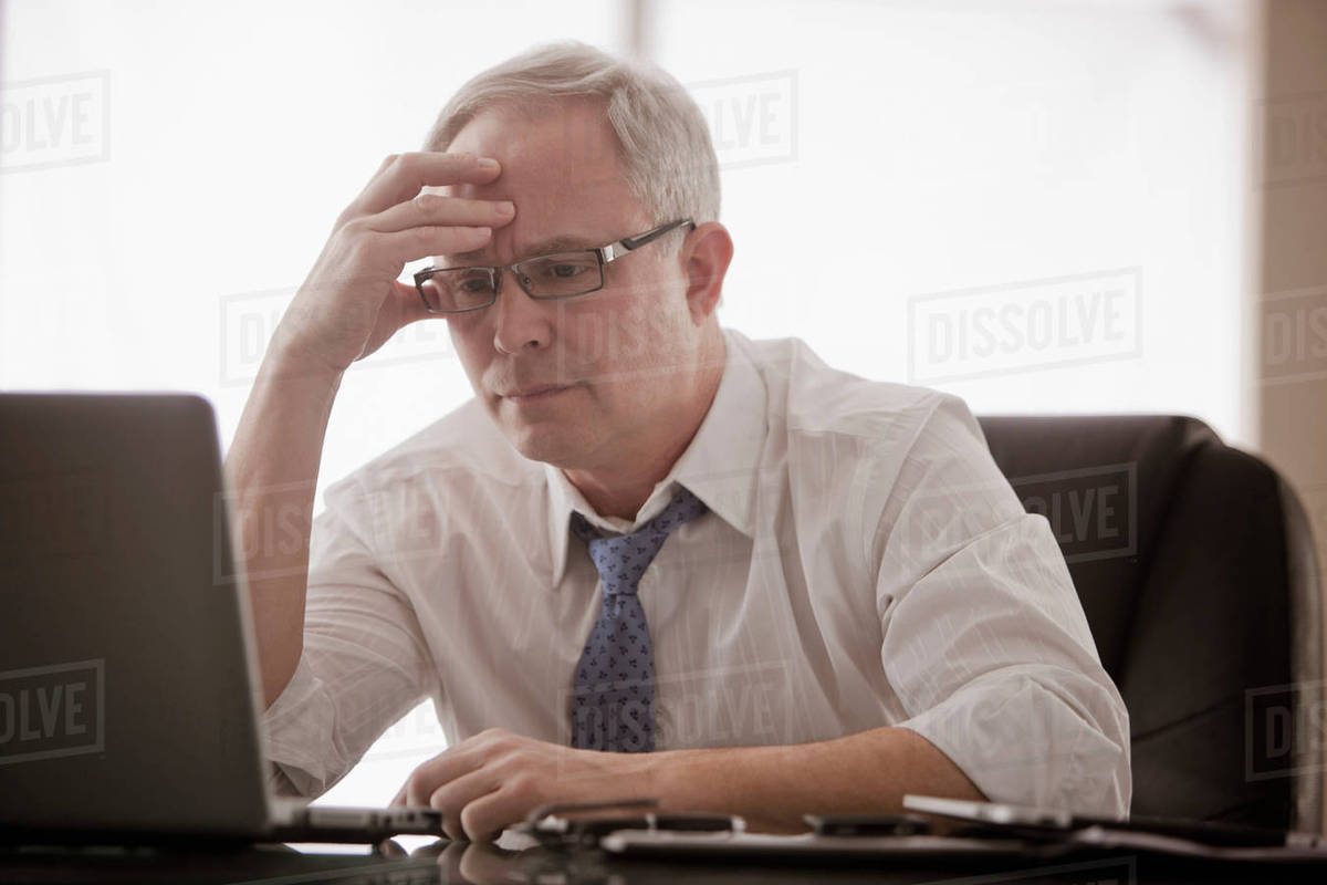 Frustrated Caucasian businessman using laptop at desk - Royalty-free ...