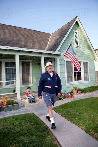 Caucasian mailman walking in front yard - Stock Photo - Dissolve