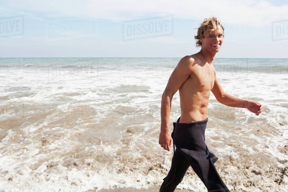 Caucasian surfer walking on beach - Stock Photo - Dissolve