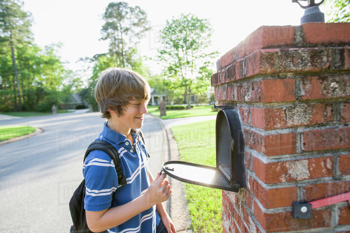 Caucasian boy opening mailbox - Royalty-free Stock Photo | Dissolve