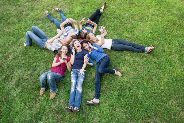 Friends hanging out together on grass - Stock Photo - Dissolve