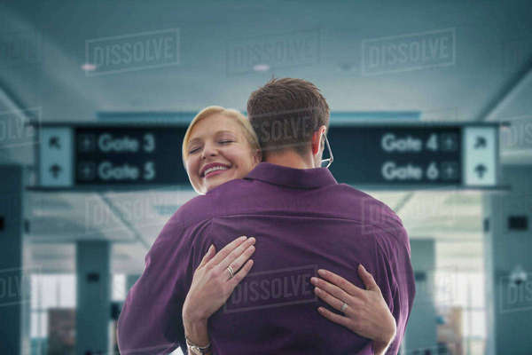 Caucasian hugging in airport - Stock Photo - Dissolve