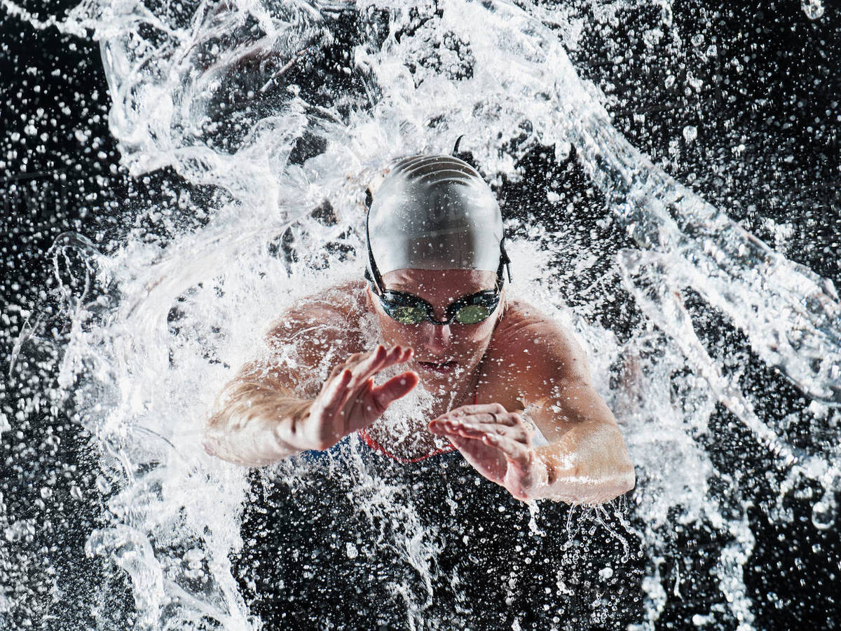 Caucasian swimmer splashing in water - Stock Photo - Dissolve