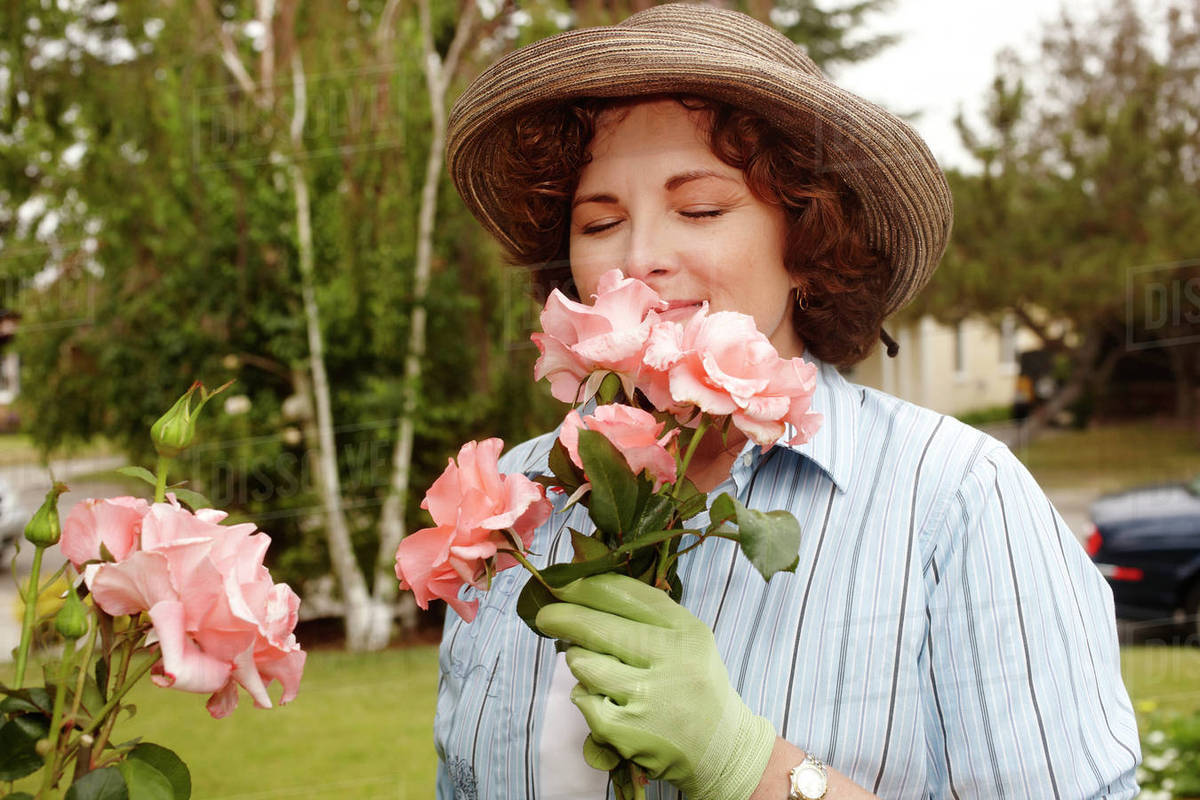 Woman smelling roses in garden - Royalty-free Stock Photo | Dissolve