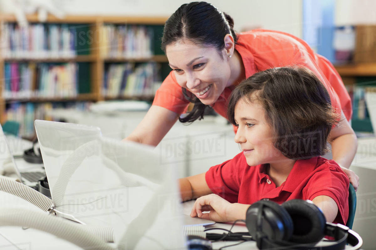 Teacher and student using laptop in library - Stock Photo - Dissolve