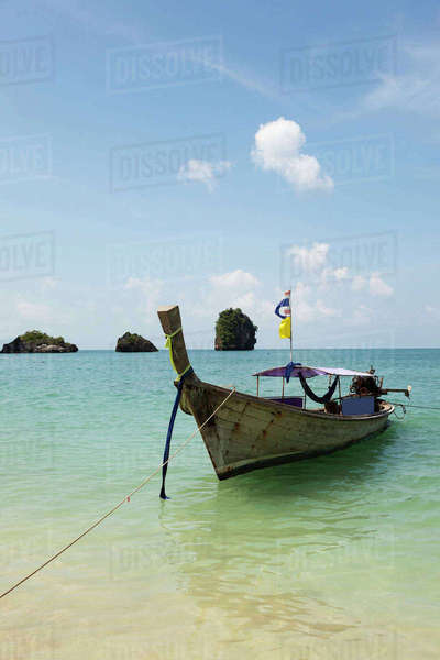 A traditional long tail boat moored in shallow water on Tham Phra Nang ...