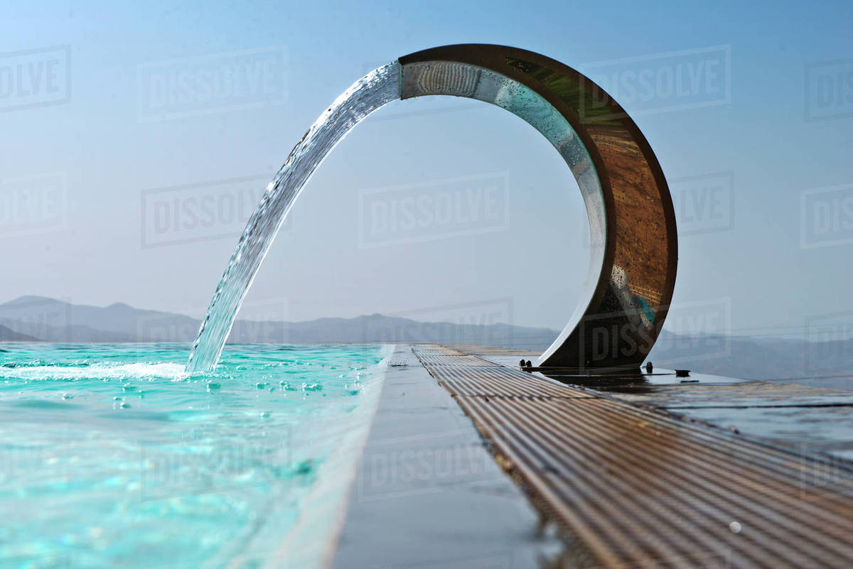 A curved stainless steel water fountain with water flowing - Royalty ...