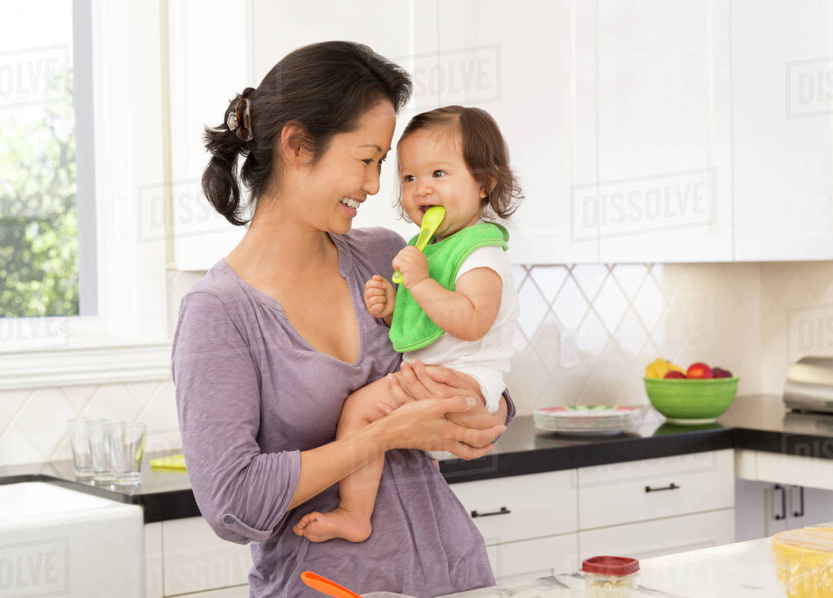 Mother holding baby girl in kitchen - Stock Photo - Dissolve