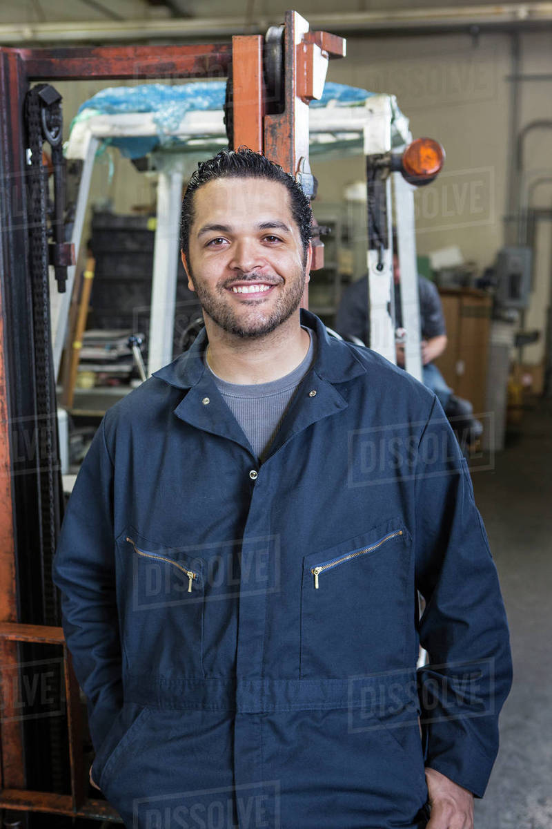 Hispanic worker smiling in warehouse - Royalty-free Stock Photo | Dissolve