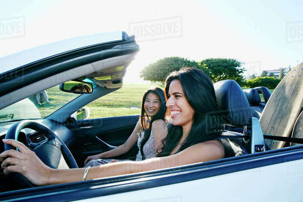 Excited women driving convertible on road trip - Stock Photo - Dissolve