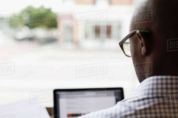 Black man using laptop at window - Stock Photo - Dissolve
