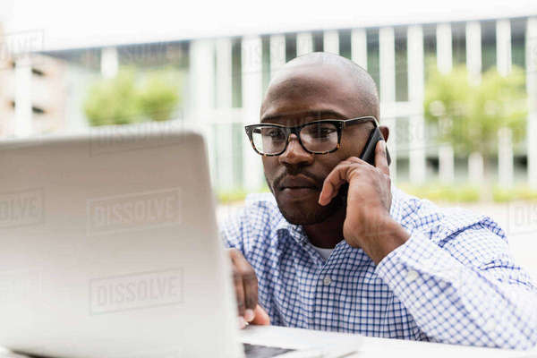 Black man using cell phone and laptop outdoors - Royalty-free Stock ...
