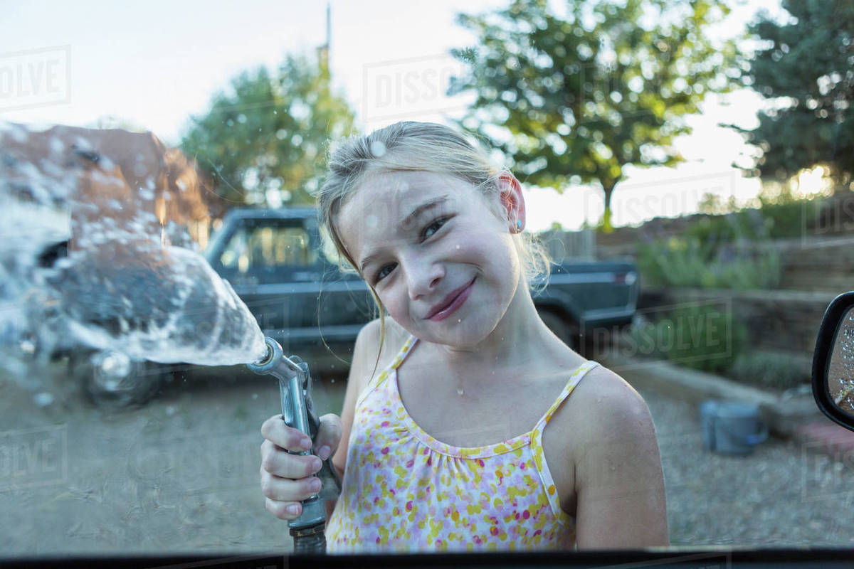 Caucasian girl spraying water from hose outdoors - Royalty-free Stock ...