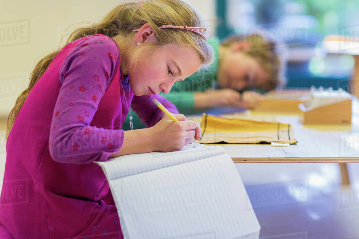 Caucasian girl writing in classroom - Royalty-free Stock Photo | Dissolve