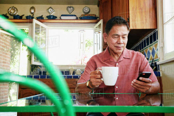 Filipino man using cell phone in kitchen - Royalty-free Stock Photo ...