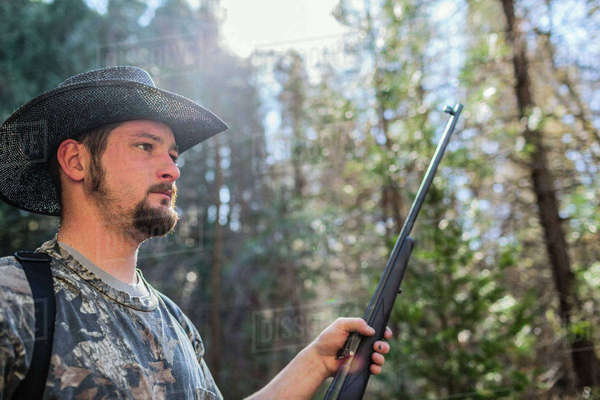 Caucasian hunter holding gun in forest - Stock Photo - Dissolve