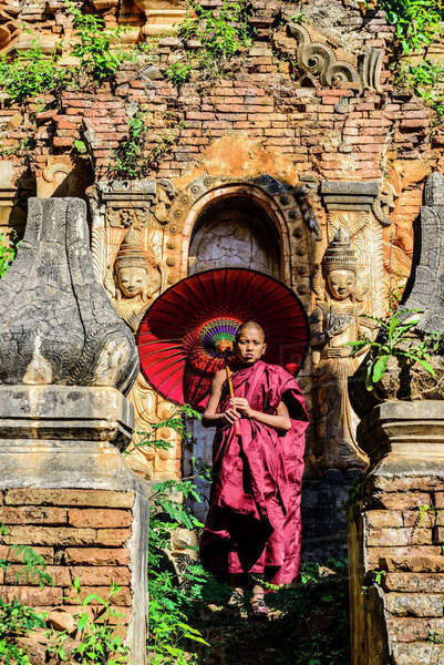Asian monk-in-training with parasol walking on Buddhist shrine ...