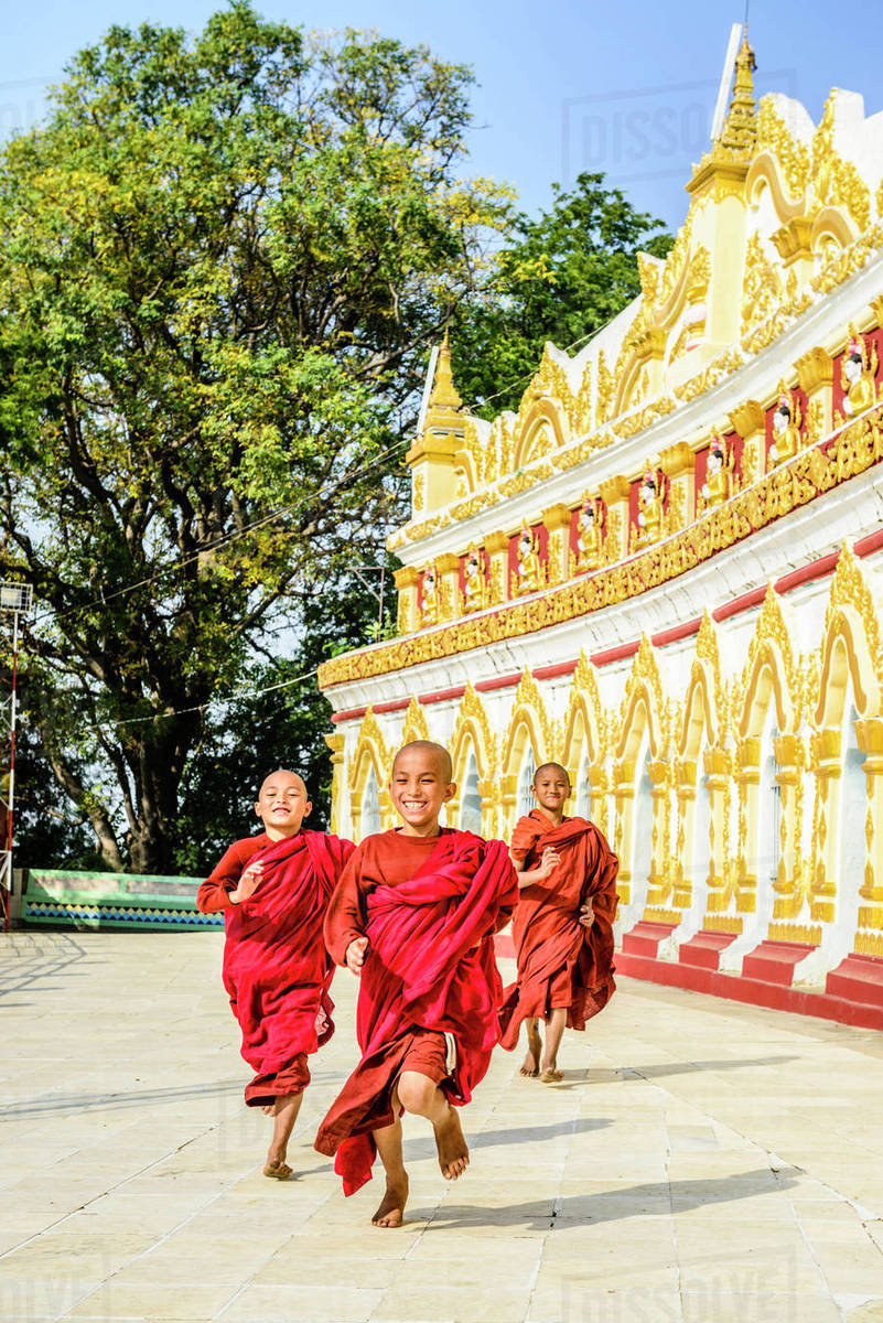 Asian monks-in-training running outside ornate temple - Royalty-free ...