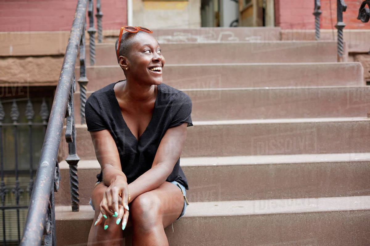 Black woman sitting on urban front stoop - Stock Photo - Dissolve