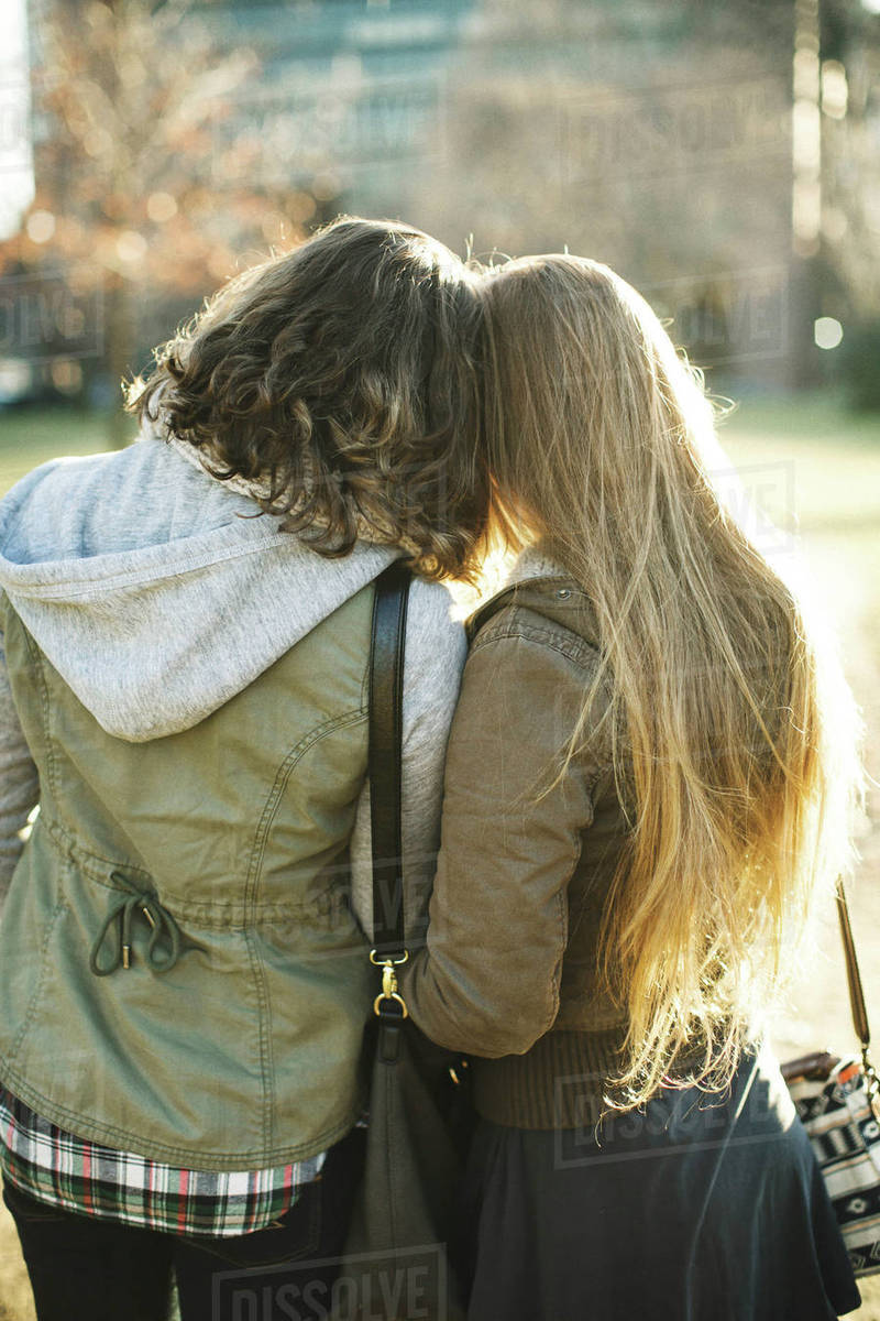 Rear view of Caucasian women hugging outdoors - Stock Photo - Dissolve