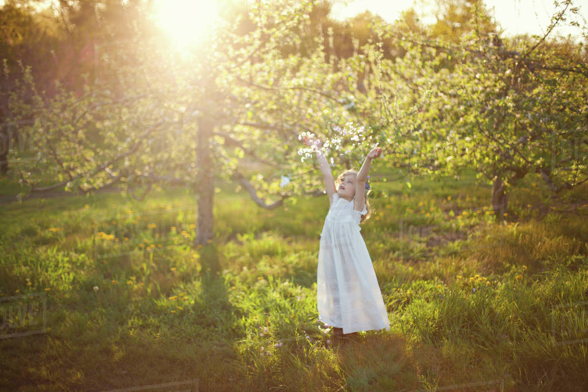 Caucasian girl tossing flower petals outdoors - Stock Photo - Dissolve
