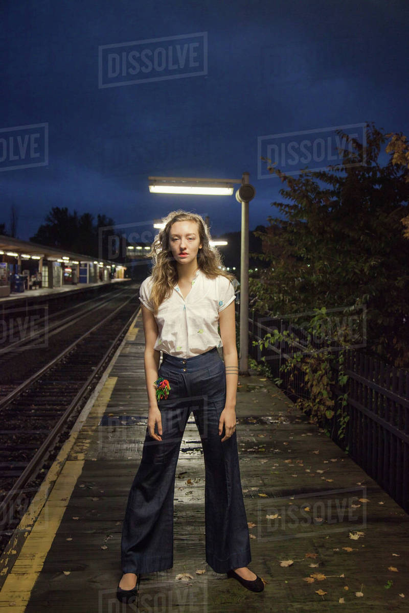 Woman waiting for train at train station at night - Stock Photo - Dissolve