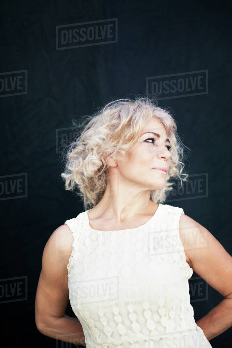 Smiling woman holding hands behind back - Stock Photo - Dissolve