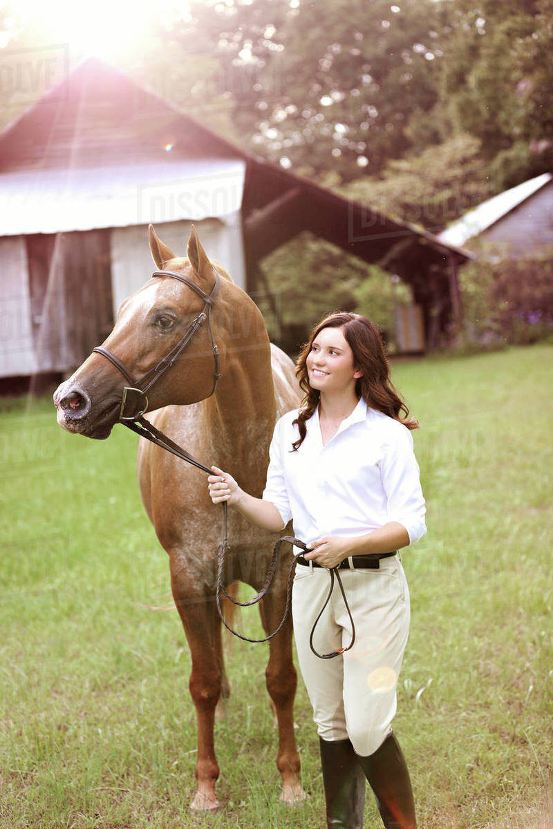 Equestrian woman walking horse in yard - Stock Photo - Dissolve