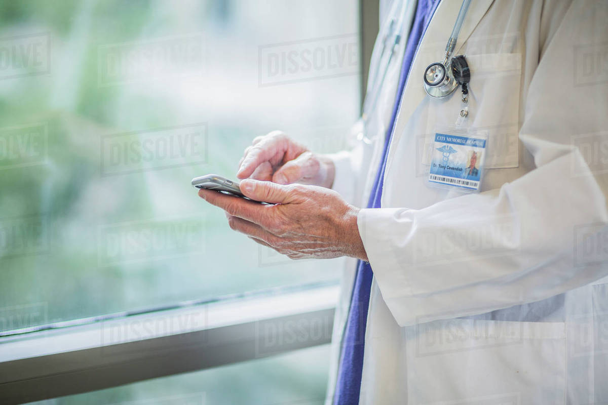 Caucasian doctor using cell phone - Royalty-free Stock Photo | Dissolve