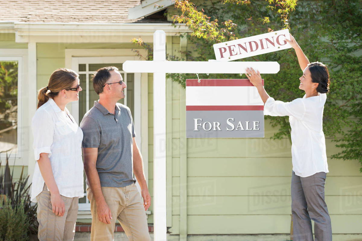 Real estate agent hanging sign outside house - Stock Photo - Dissolve