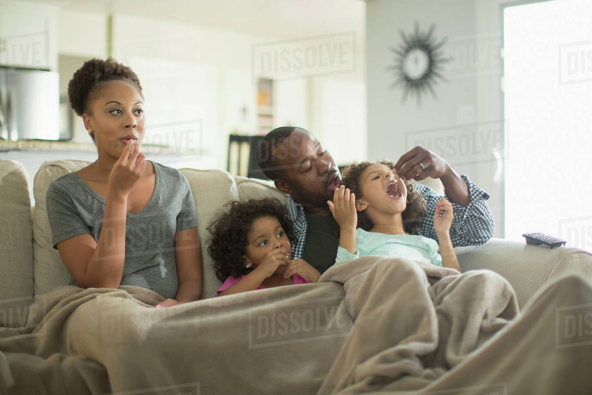 Family in blanket snacking on sofa - Royalty-free Stock Photo | Dissolve