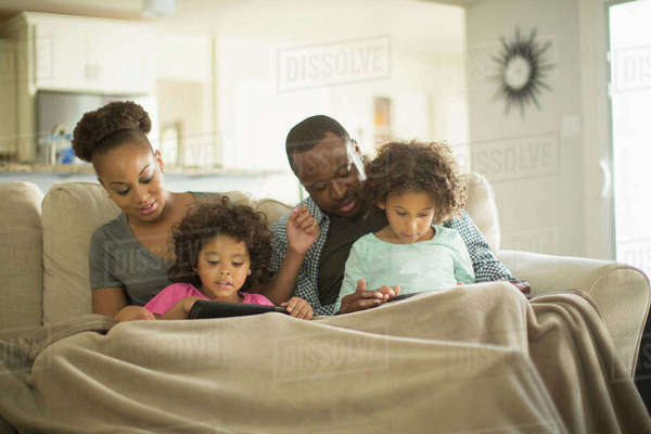 Family using digital tablets on sofa - Stock Photo - Dissolve