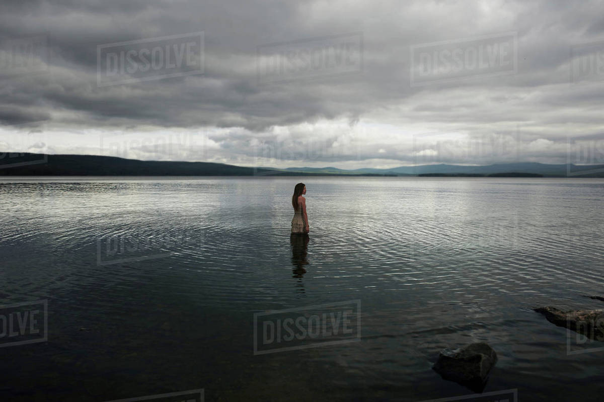 Caucasian girl wading in lake - Royalty-free Stock Photo | Dissolve