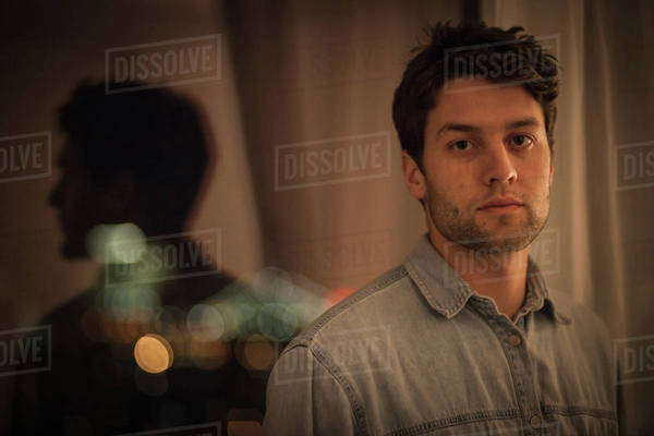 Caucasian man standing near window at night - Stock Photo - Dissolve