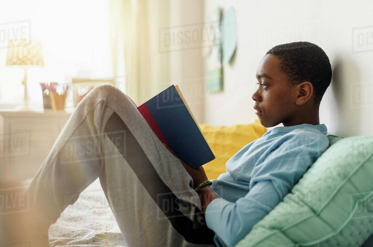 Black boy reading book on bed - Royalty-free Stock Photo | Dissolve