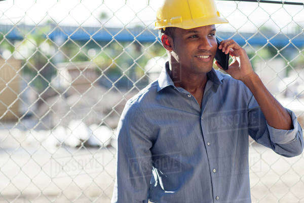 Black architect in hard hat talking on cell phone - Royalty-free Stock ...