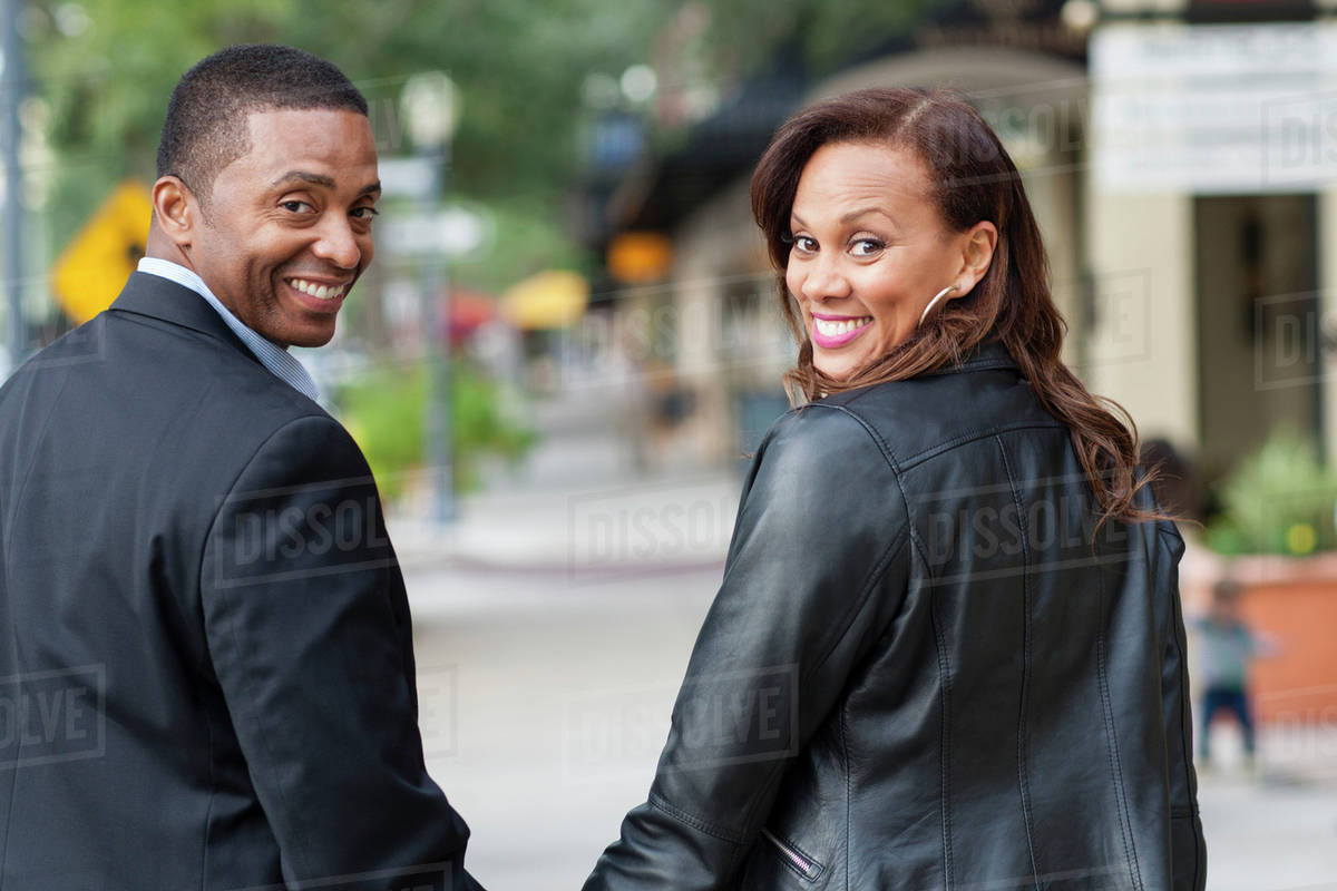 Couple looking over shoulders in city - Royalty-free Stock Photo | Dissolve