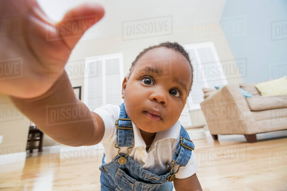 Black baby reaching for camera on living room floor - Royalty-free ...