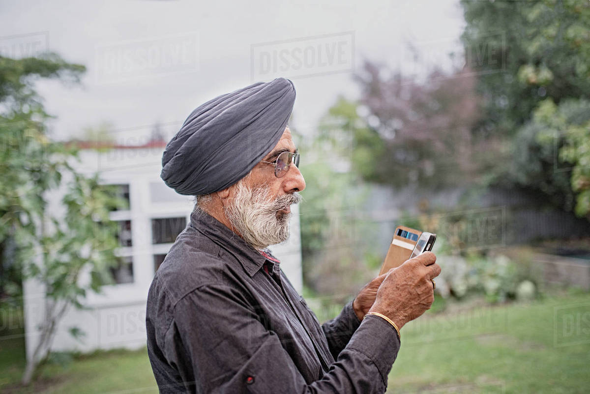 Indian man texting on cell phone - Stock Photo - Dissolve